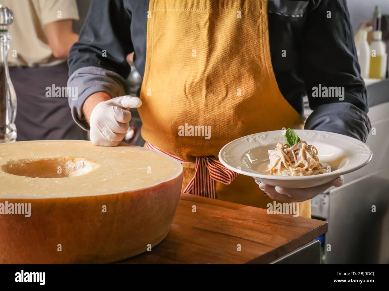 Male chef holding plate with tasty pasta in restaurant kitchen Stock ...