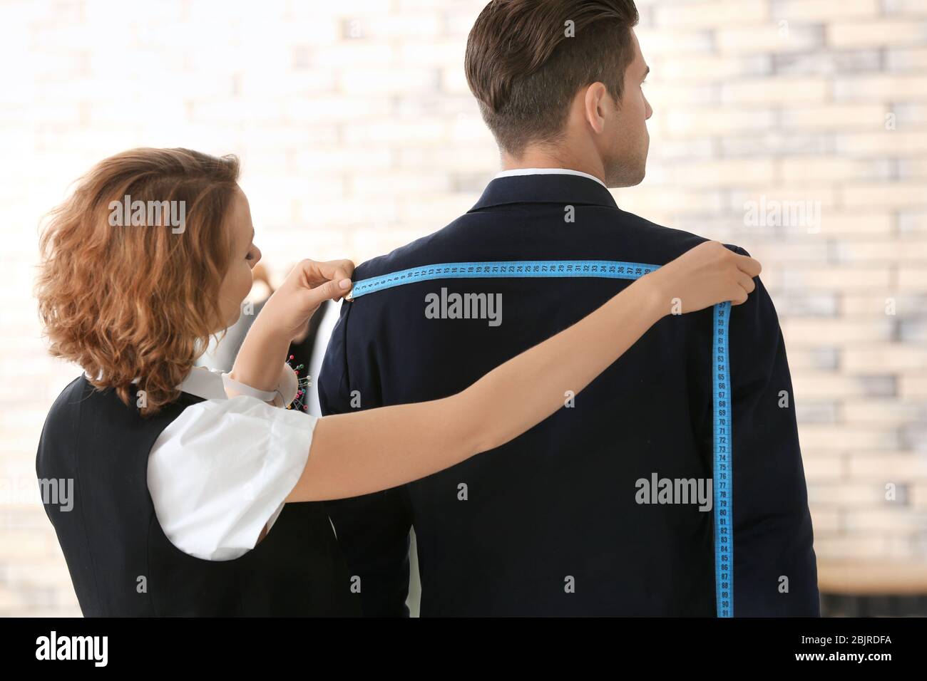Seamstress taking client's measurements in atelier Stock Photo - Alamy