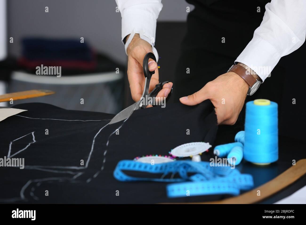 Young tailor cutting out suit detail in atelier Stock Photo - Alamy