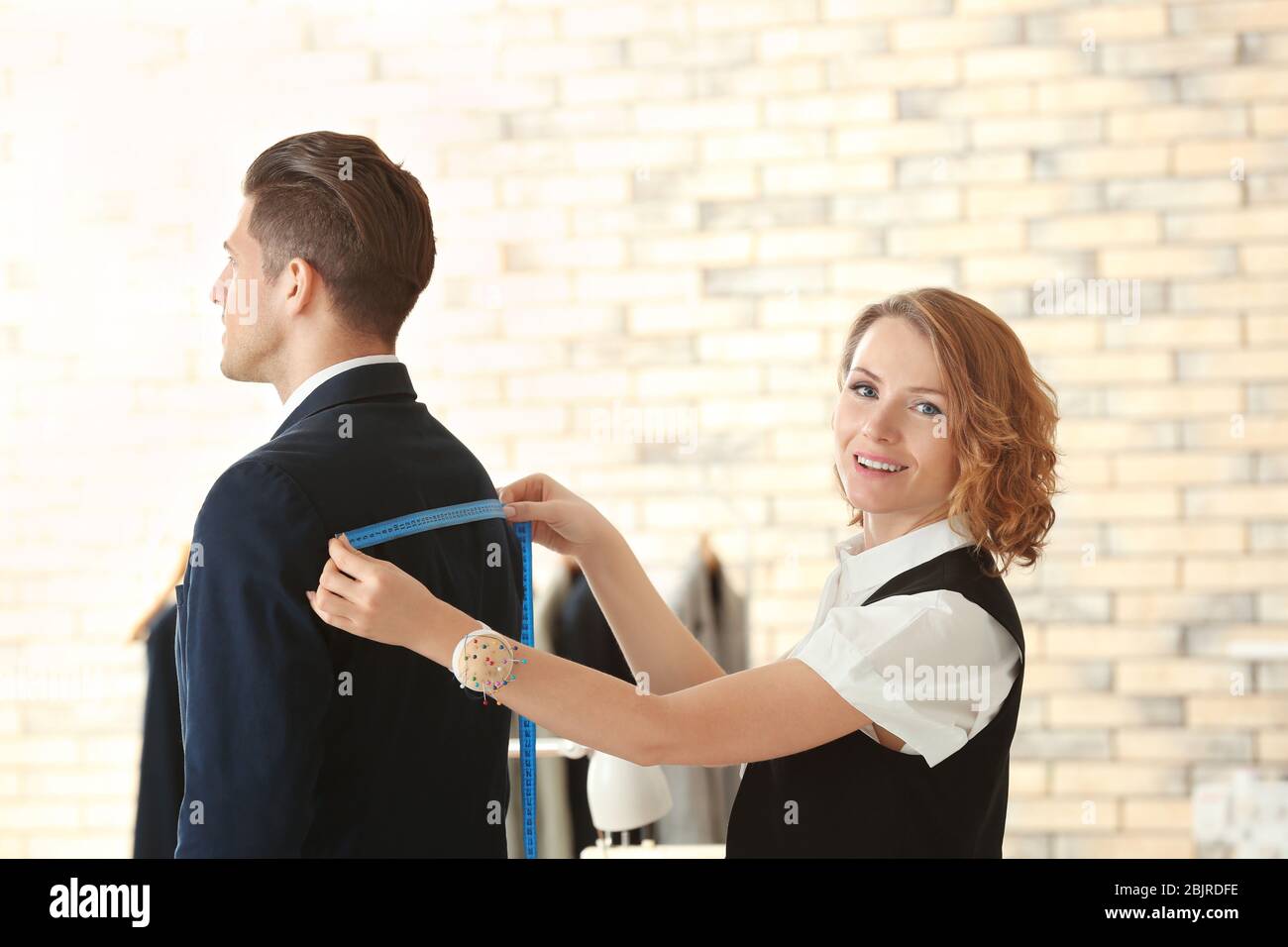 Seamstress taking client's measurements in atelier Stock Photo - Alamy