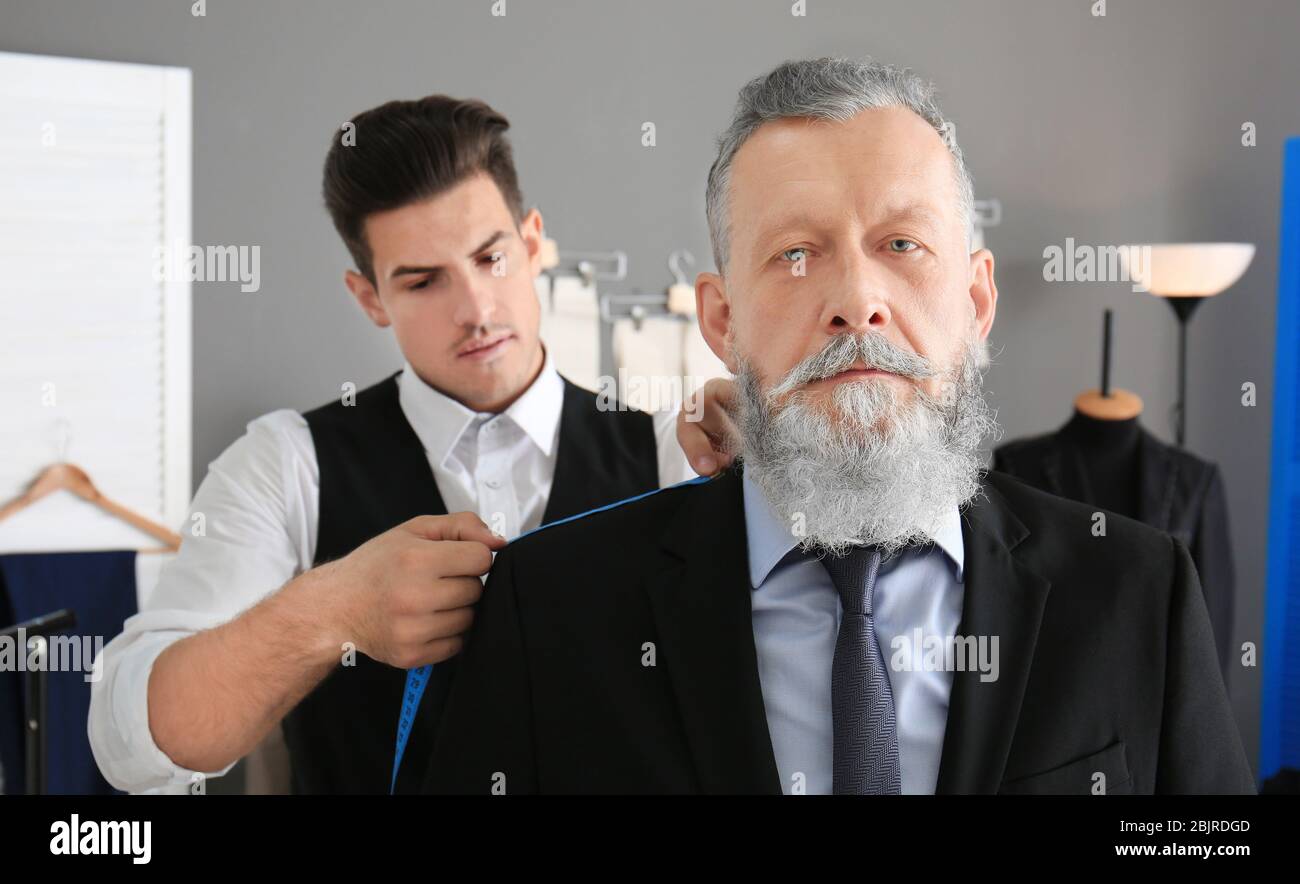 Tailor taking client's measurements in atelier Stock Photo - Alamy