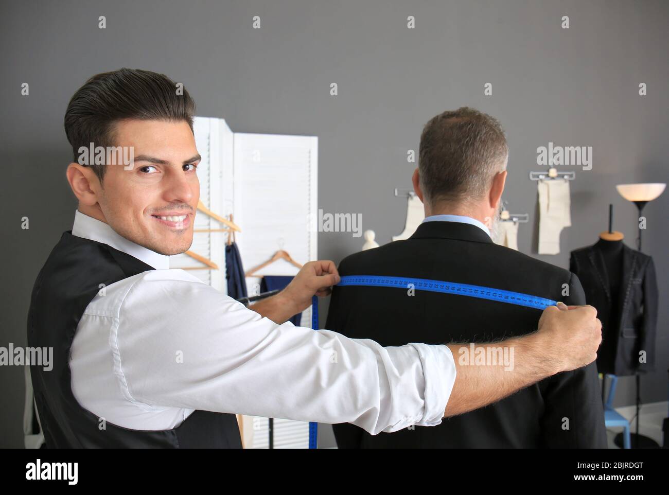 Tailor taking client's measurements in atelier Stock Photo - Alamy
