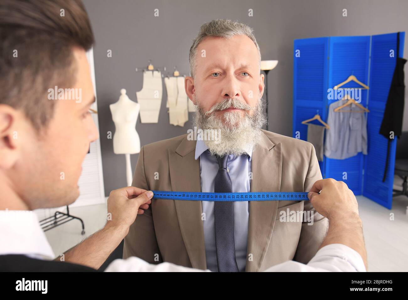 Tailor taking client's measurements in atelier Stock Photo - Alamy
