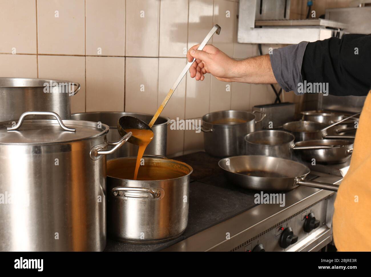 Male chef cooking sauce in restaurant kitchen Stock Photo - Alamy