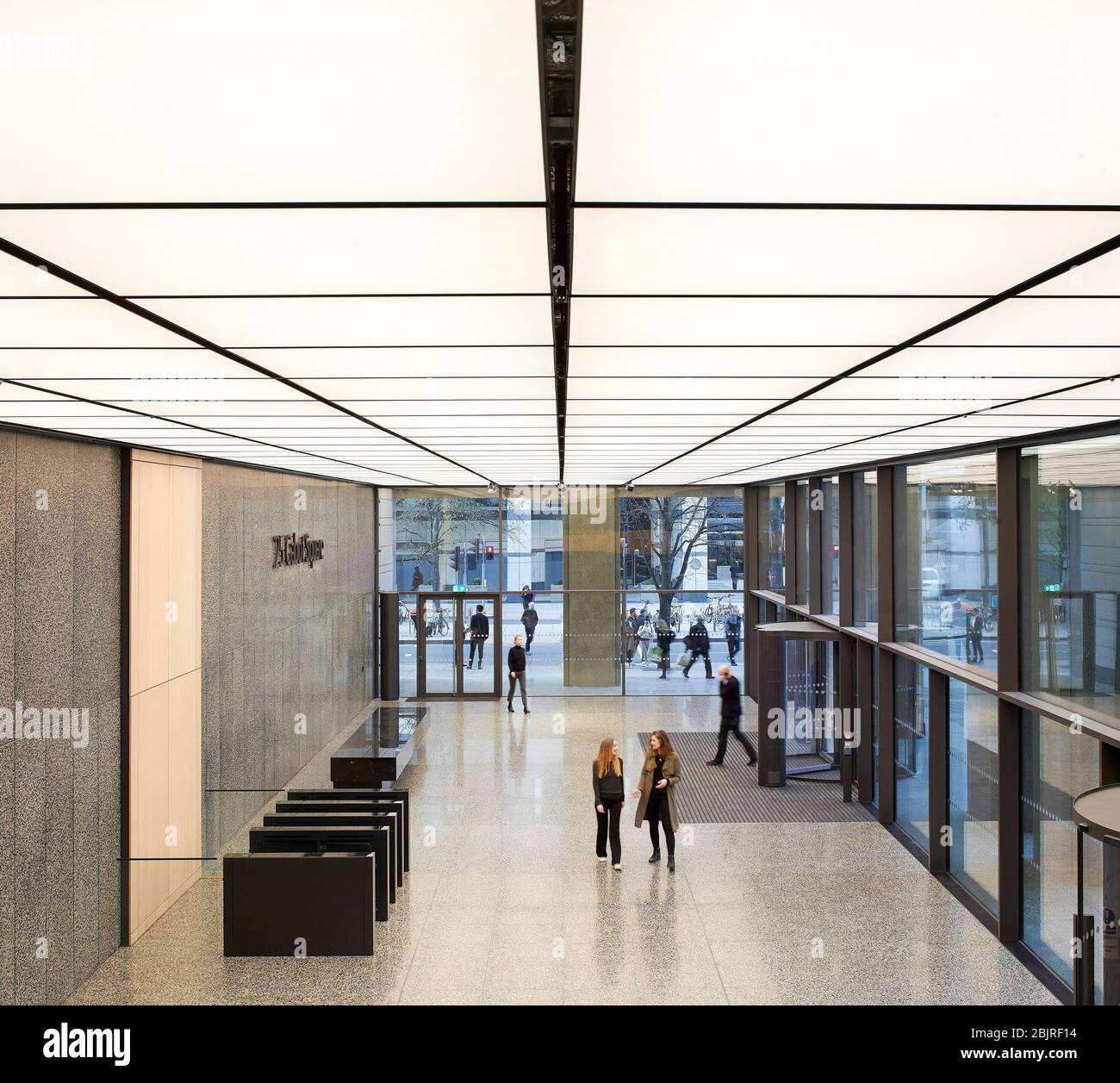 Corporate reception space with illuminated ceiling and security gates ...