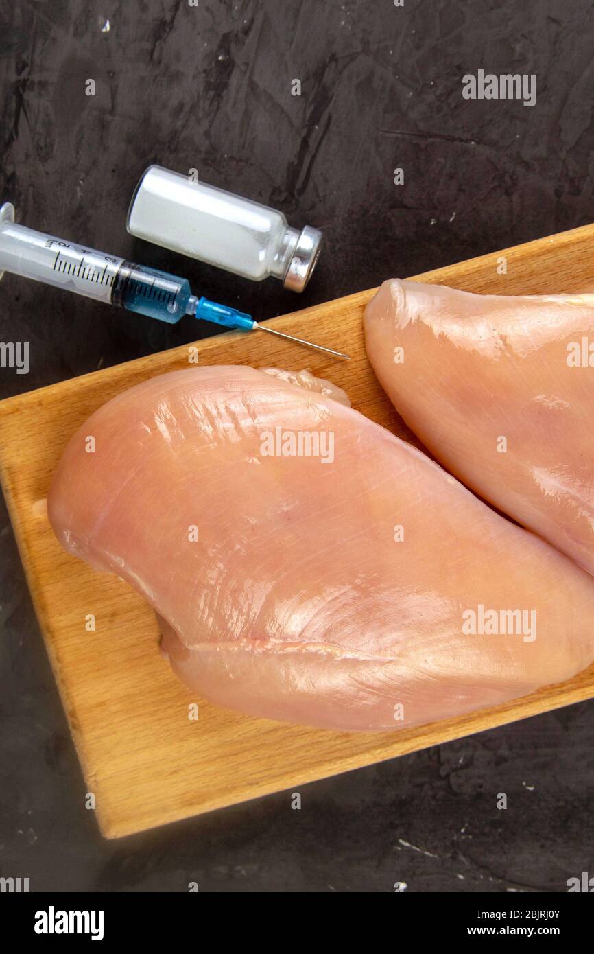 Injection syringe in raw chicken pieces, concept of injection of GMOs ...