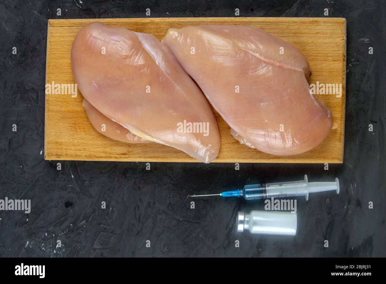 Injection syringe in raw chicken pieces, concept of injection of GMOs ...