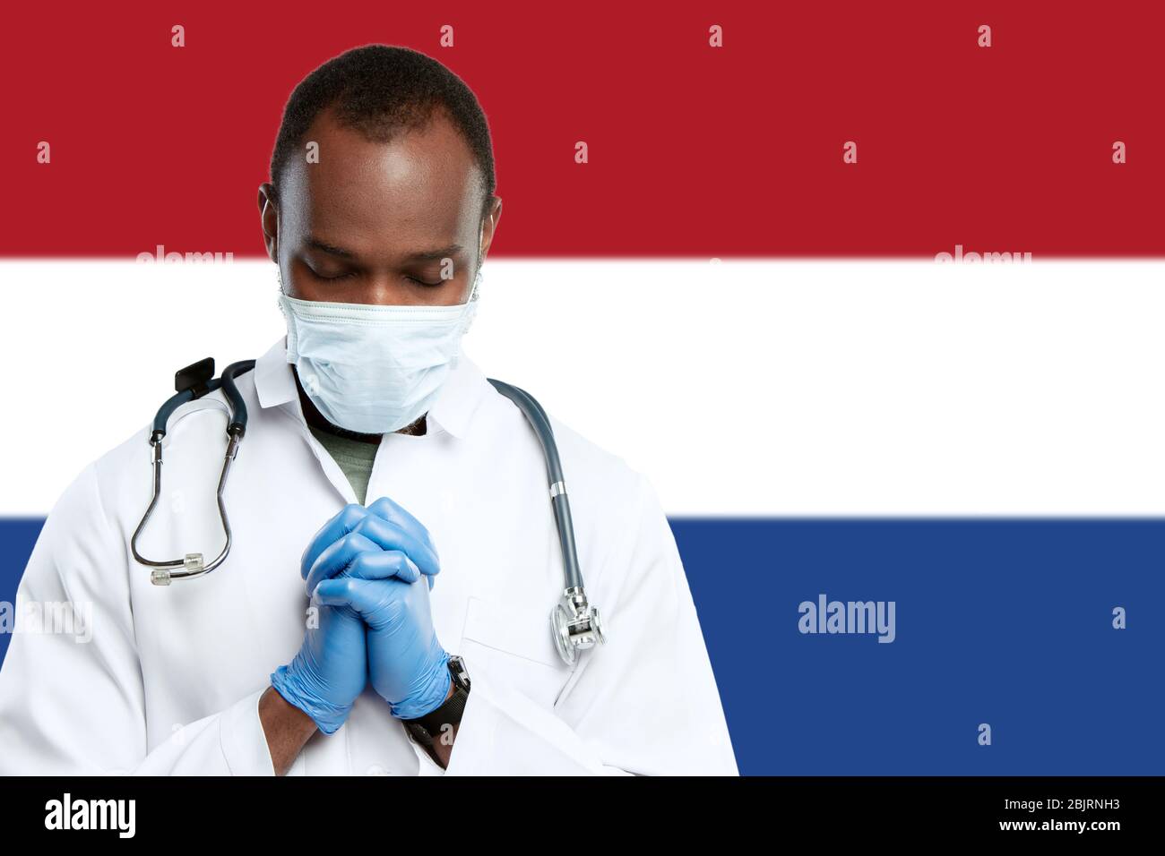 Young doctor with stethoscope and face mask praying for God with ...