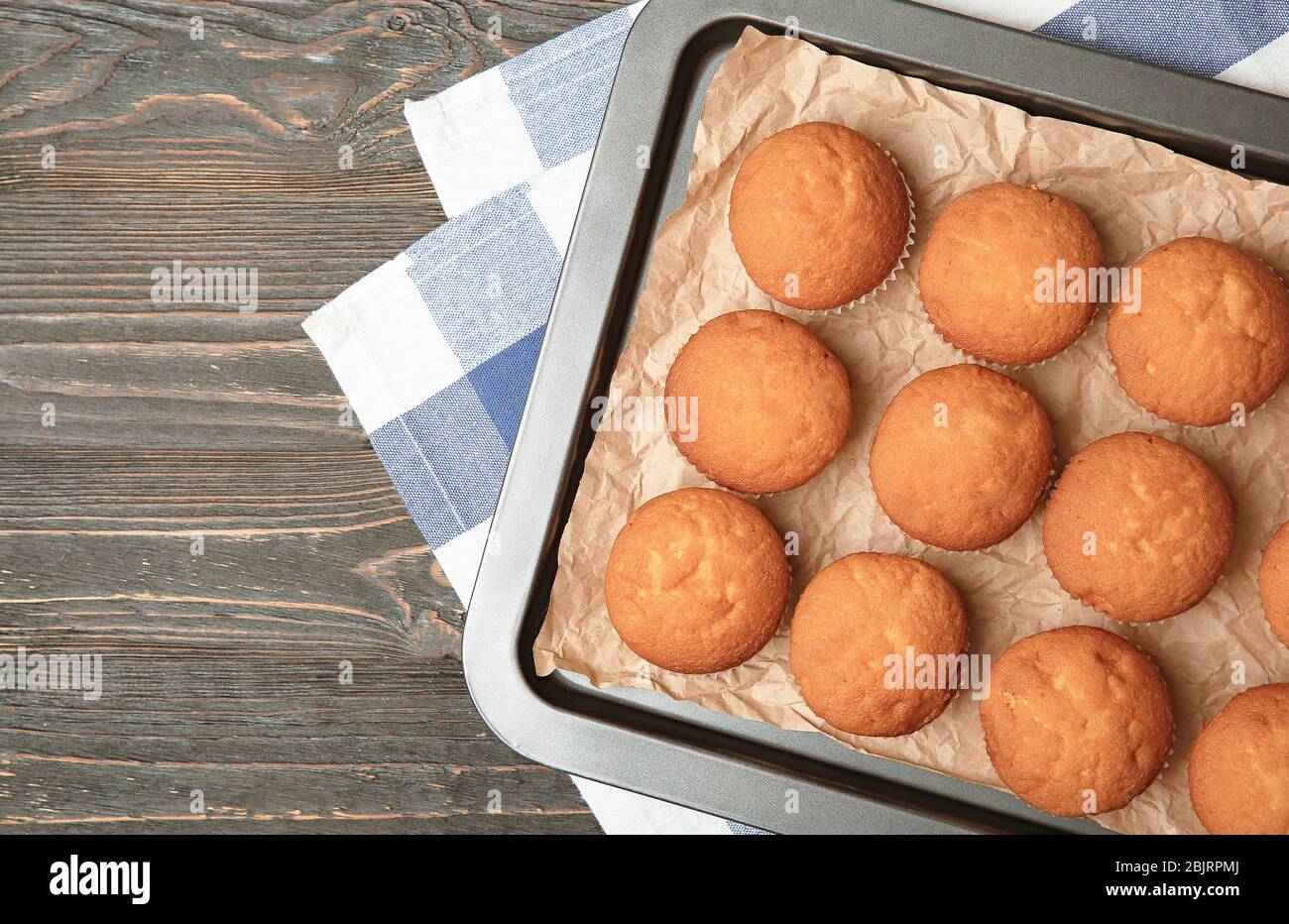 Baking sheet with delicious cupcakes on wooden table, top view Stock ...