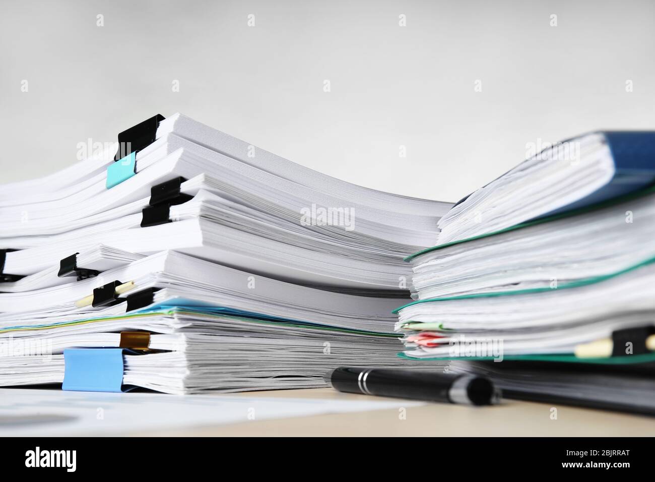 Stacks of documents on table against light background Stock Photo - Alamy
