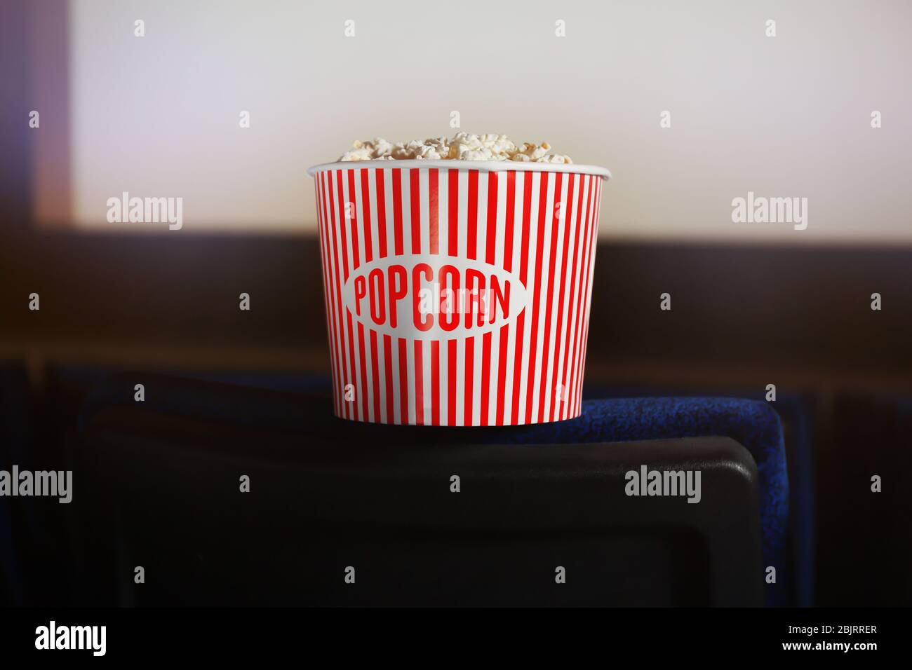 Bucket with tasty popcorn on cinema chair Stock Photo - Alamy