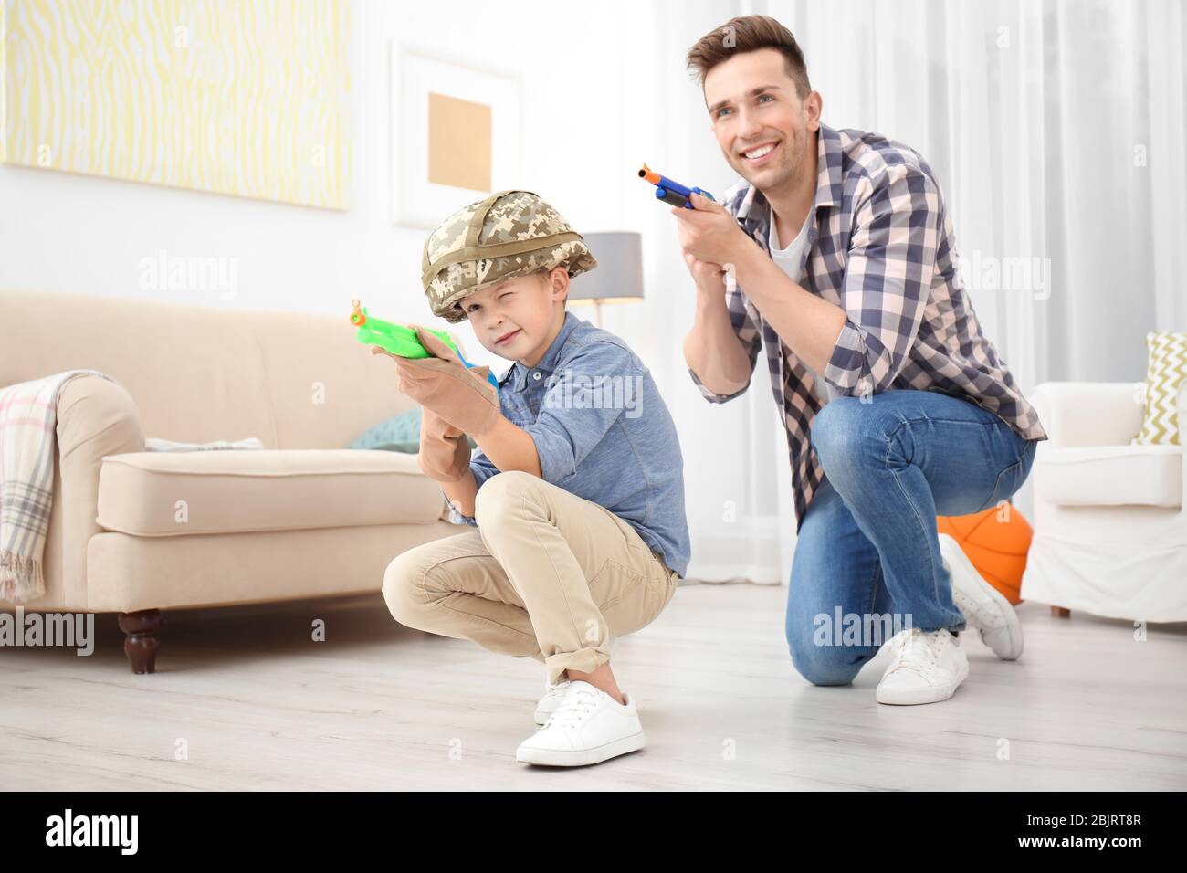 Cute boy and his father playing with toy guns at home Stock Photo - Alamy