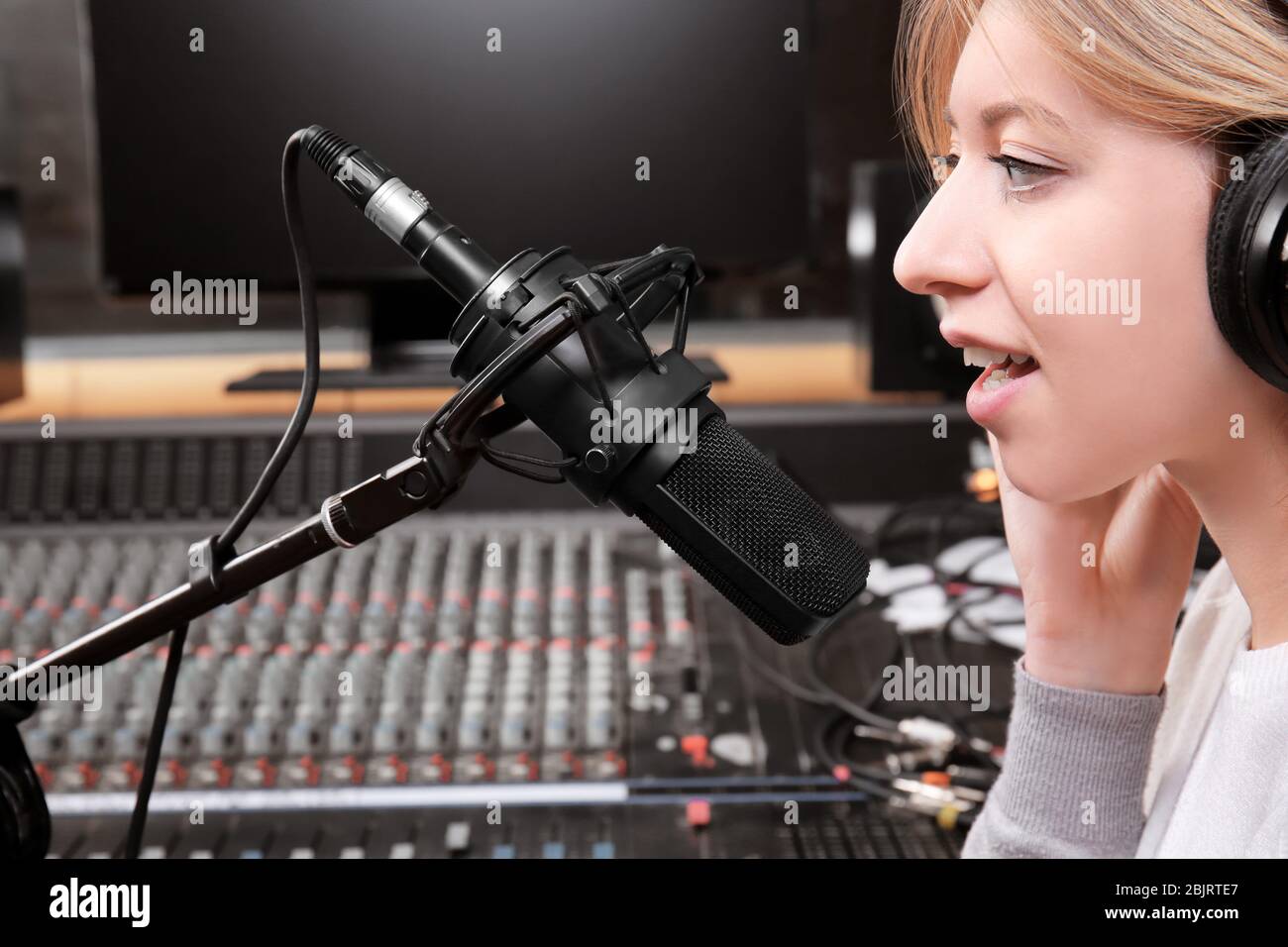 Female radio host broadcasting through microphone in studio Stock Photo ...