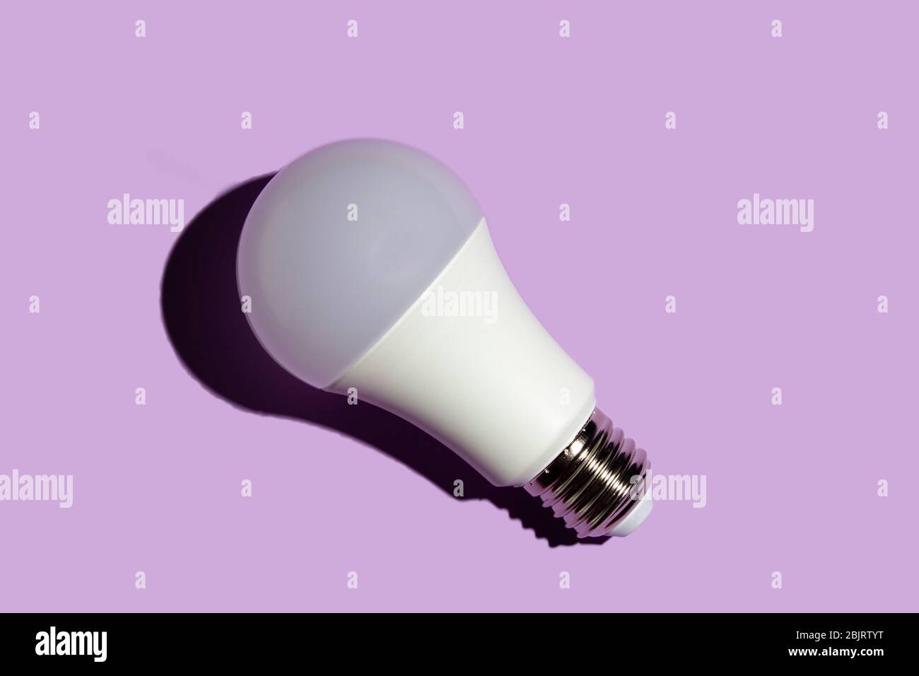 LED light bulb with hard shadows on a purple background Stock Photo - Alamy