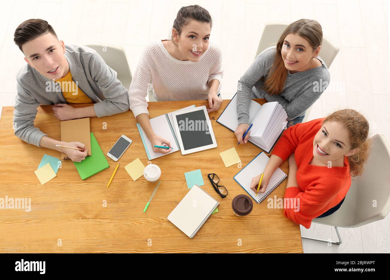 Group of teenagers studying at table indoors Stock Photo - Alamy