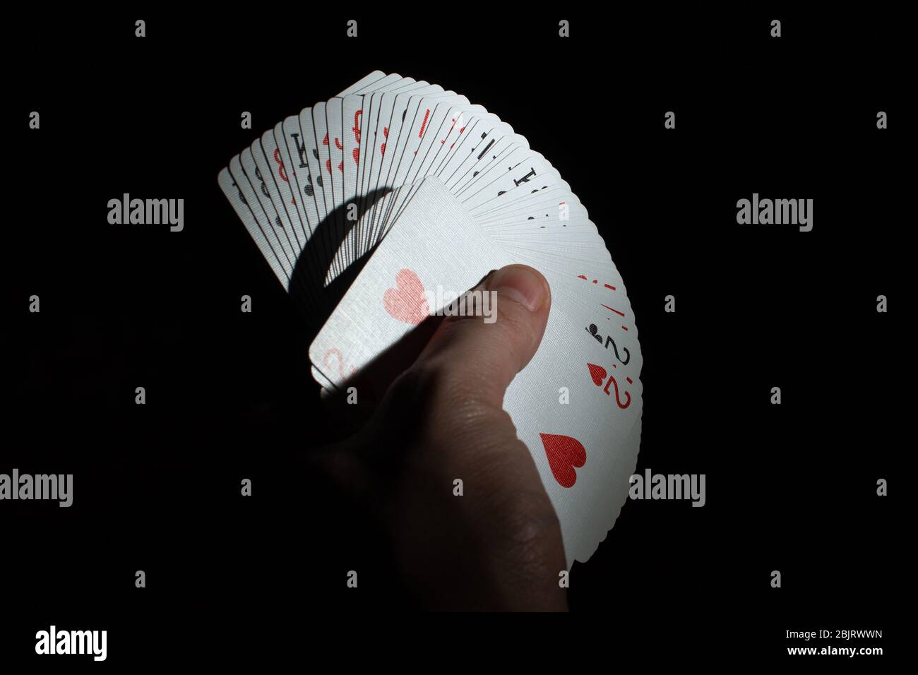 hand hold a fan from a deck of poker cards on a black background copy ...