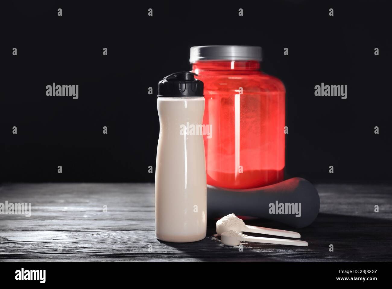 Composition with protein powder, shake and dumbbell on table against ...