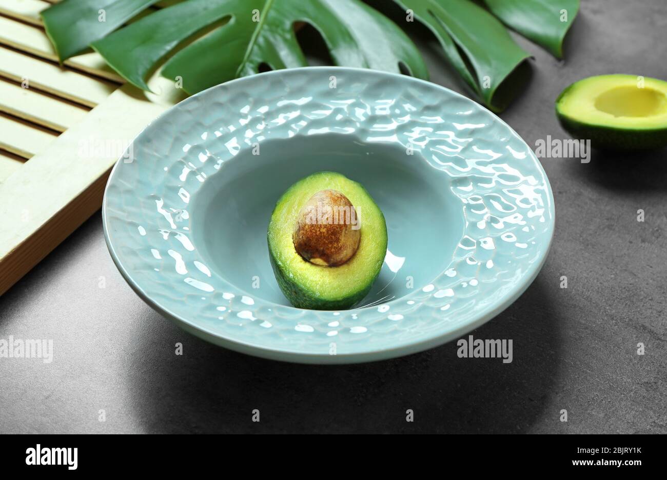 Ceramic plate with avocado on grey background Stock Photo - Alamy