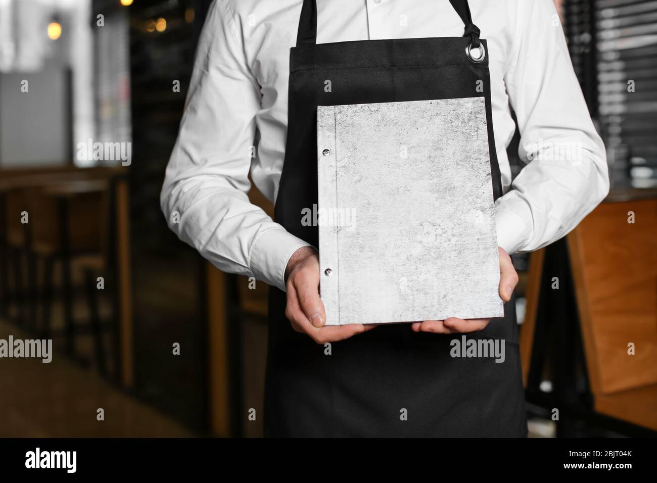 Waiter holding menu in restaurant Stock Photo - Alamy