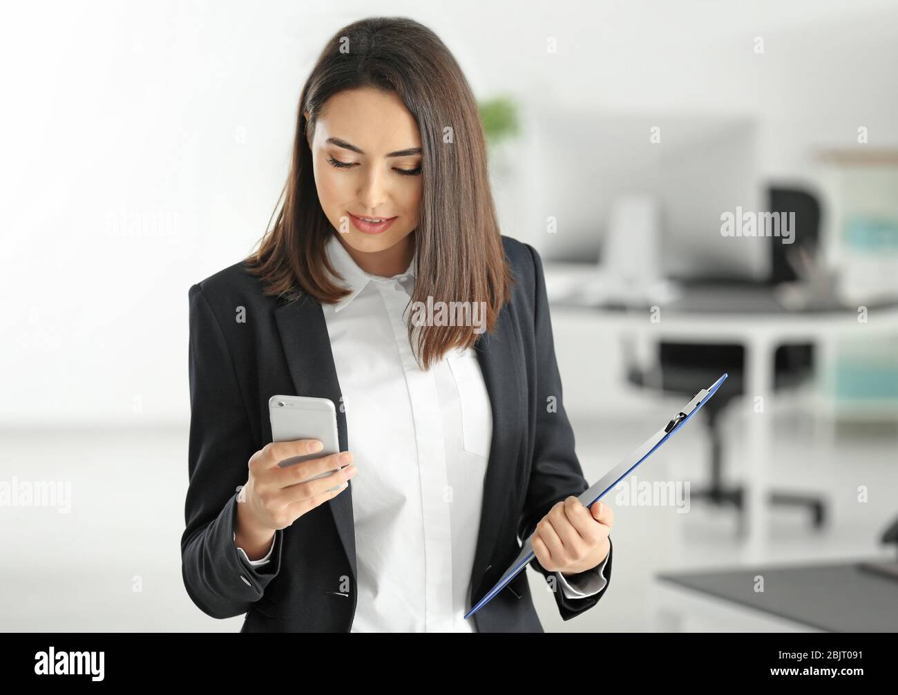 Attractive young lawyer with mobile phone in office Stock Photo - Alamy