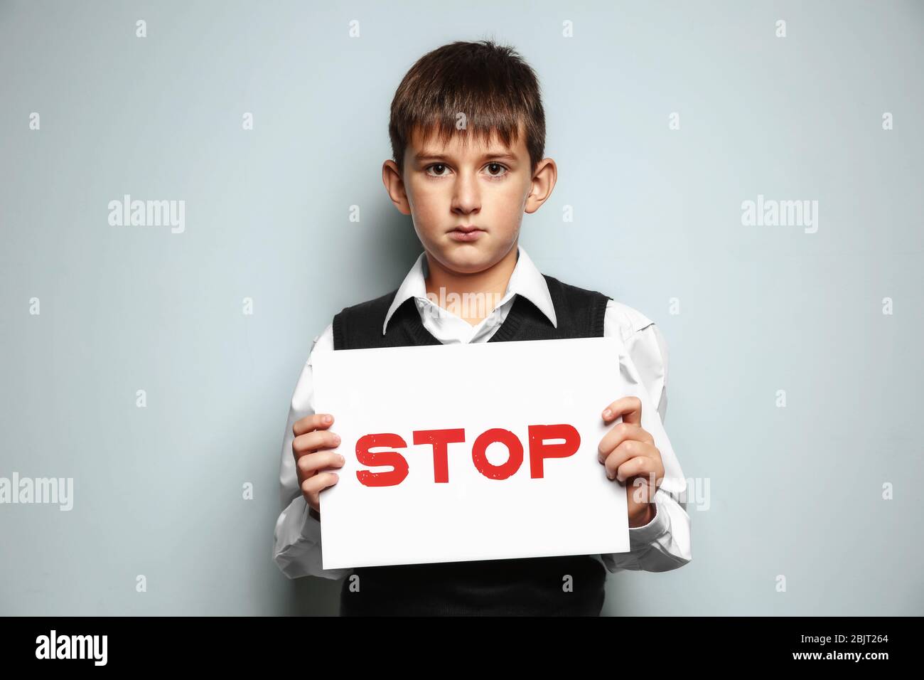 Little boy holding sign with word "Stop" on light background Stock ...