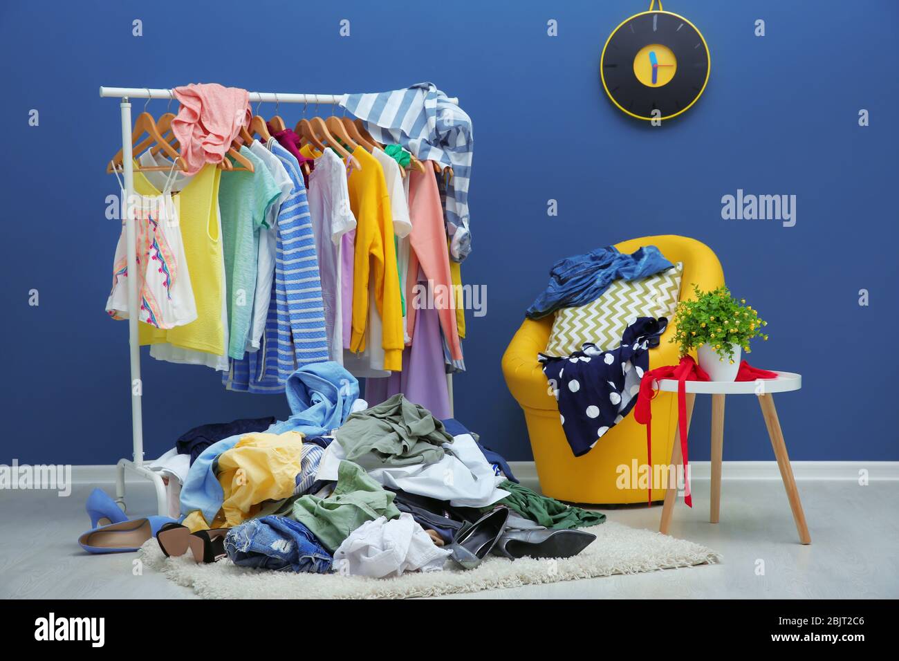Messy dressing room interior with clothes rack and stylish armchair ...