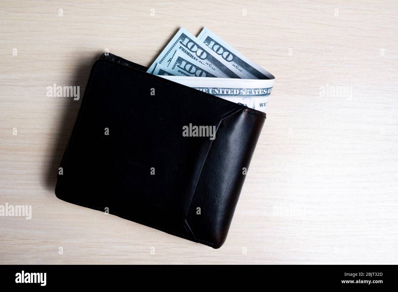 bundle of dollar bill in black leather wallet on a light wooden ...
