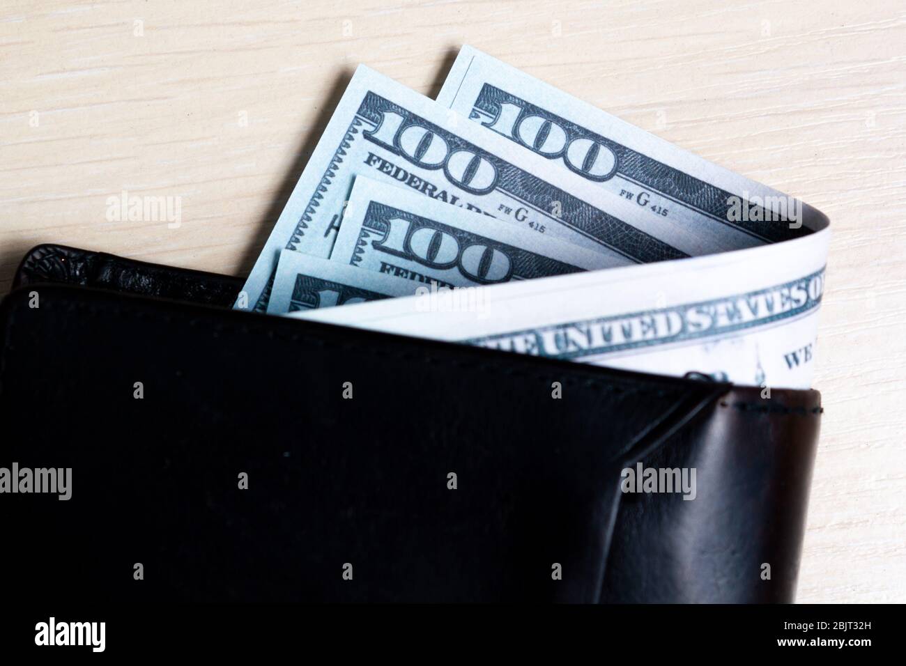 bundle of dollar bill in black leather wallet on a light wooden ...