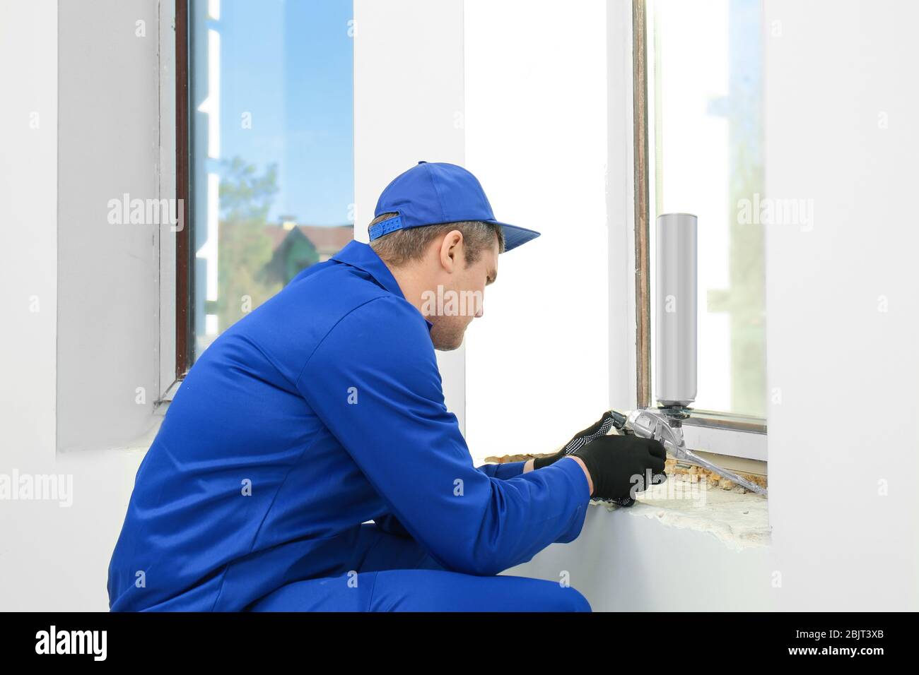 Construction worker repairing window in house Stock Photo - Alamy