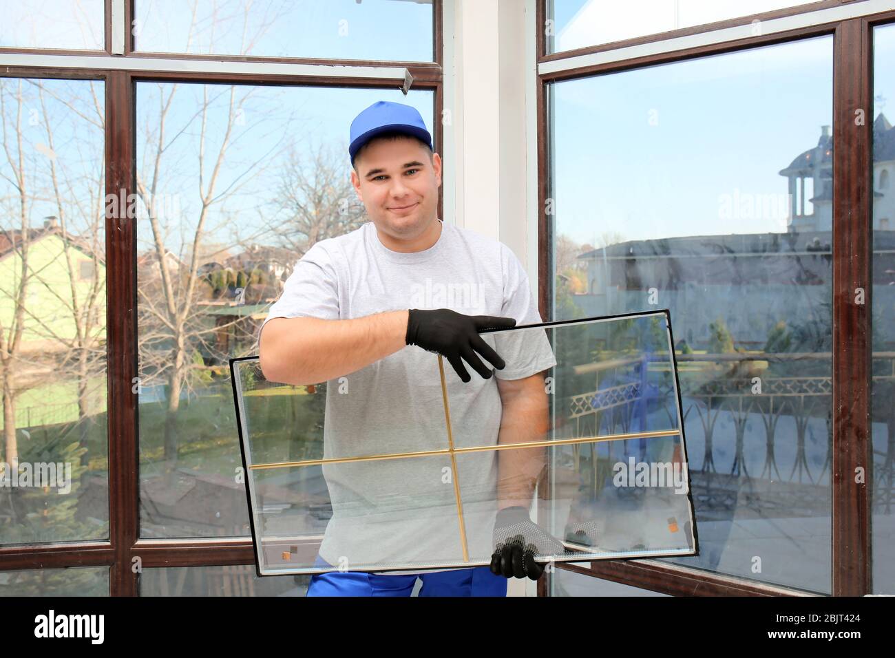 Construction worker holding window glass indoors Stock Photo - Alamy