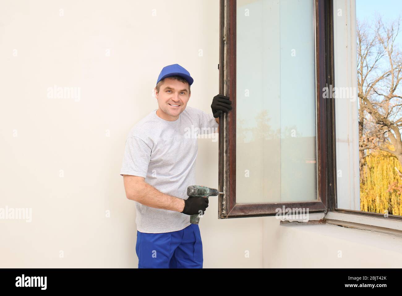 Construction worker repairing window in house Stock Photo - Alamy