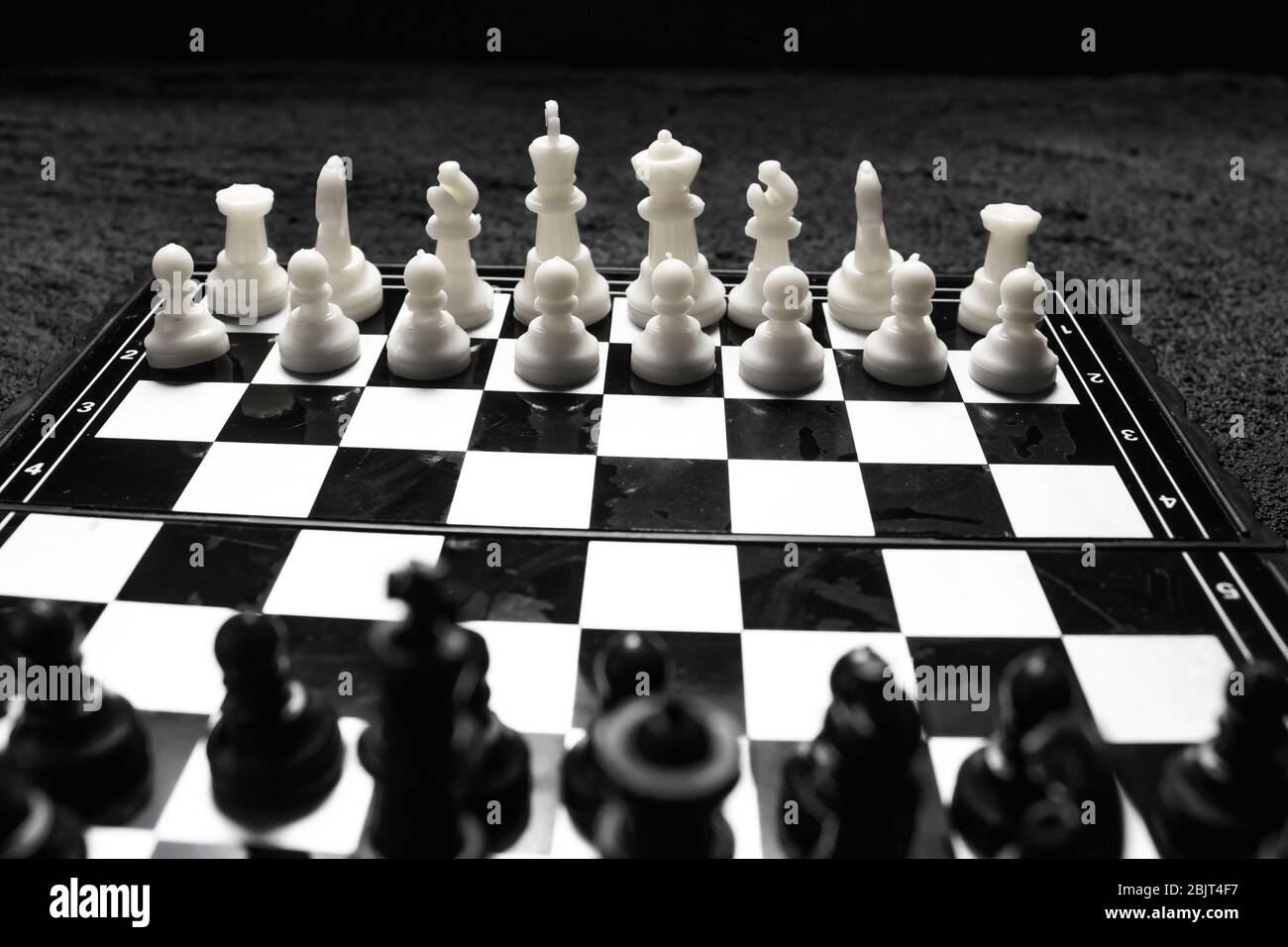 chessboard layout of white and black pawn figures on black concrete ...
