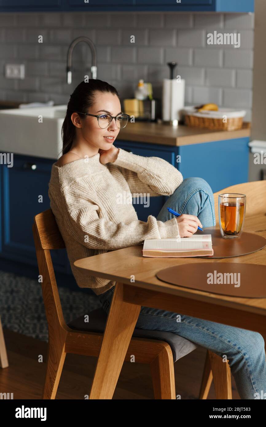 Photo of a concentrated young woman indoors at home drinking tea ...