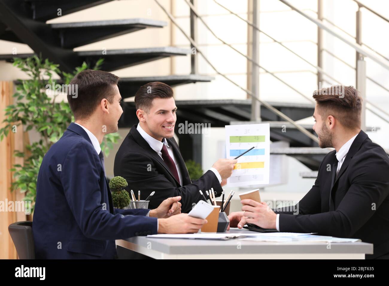 Men in elegant suits having meeting at workplace Stock Photo - Alamy