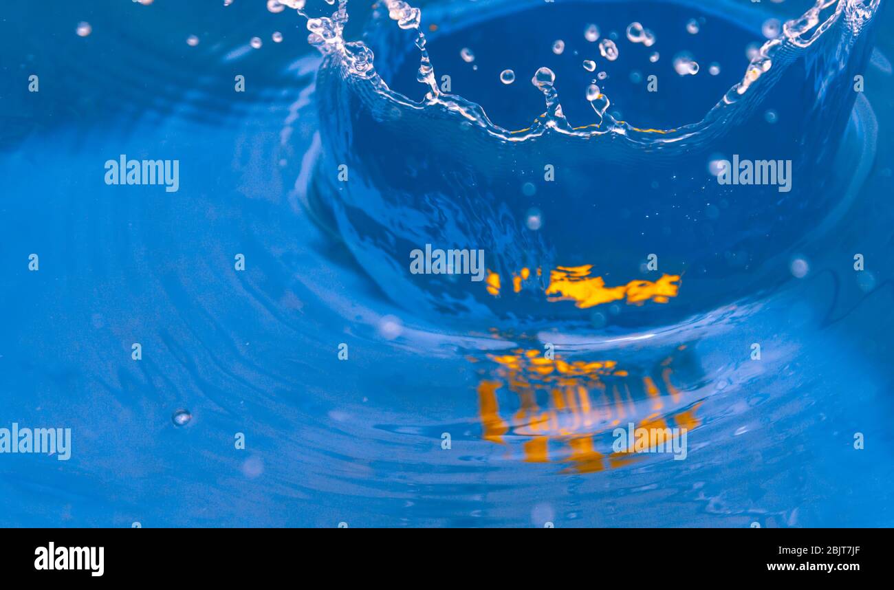 mandorine drops in blue water with splashes Stock Photo - Alamy