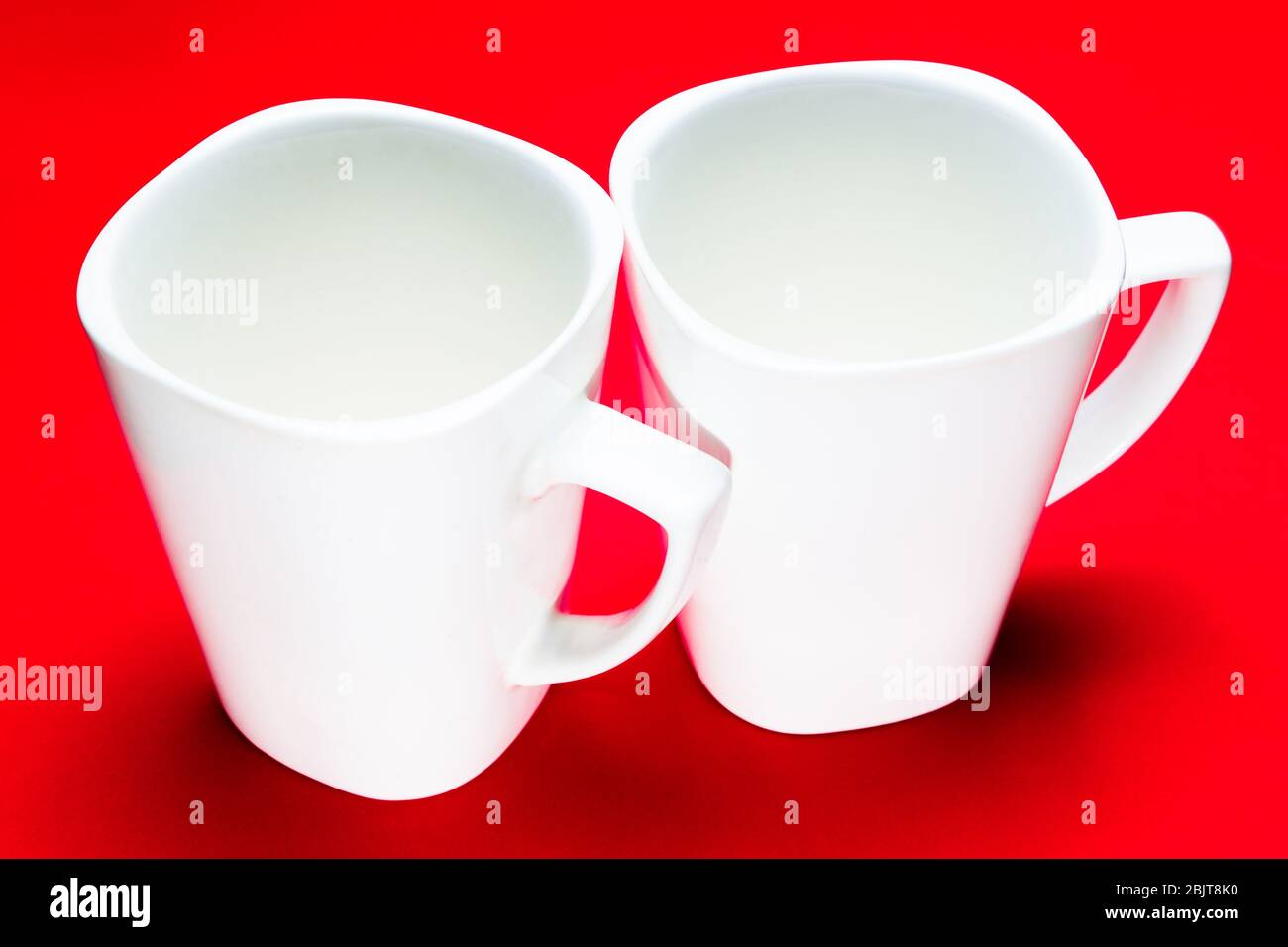 Two white square cup on a red background Stock Photo - Alamy