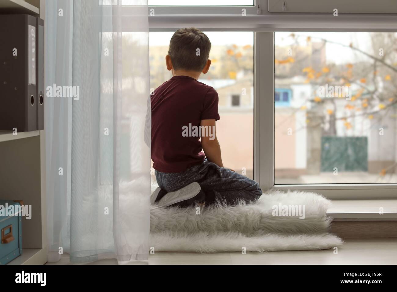 Little boy sitting near window at home. Child autism Stock Photo - Alamy