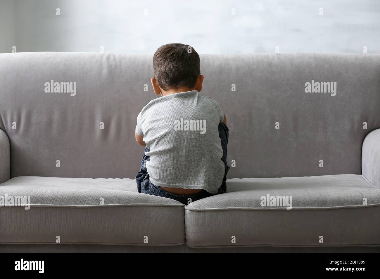 Little boy sitting on sofa at home. Child autism Stock Photo - Alamy
