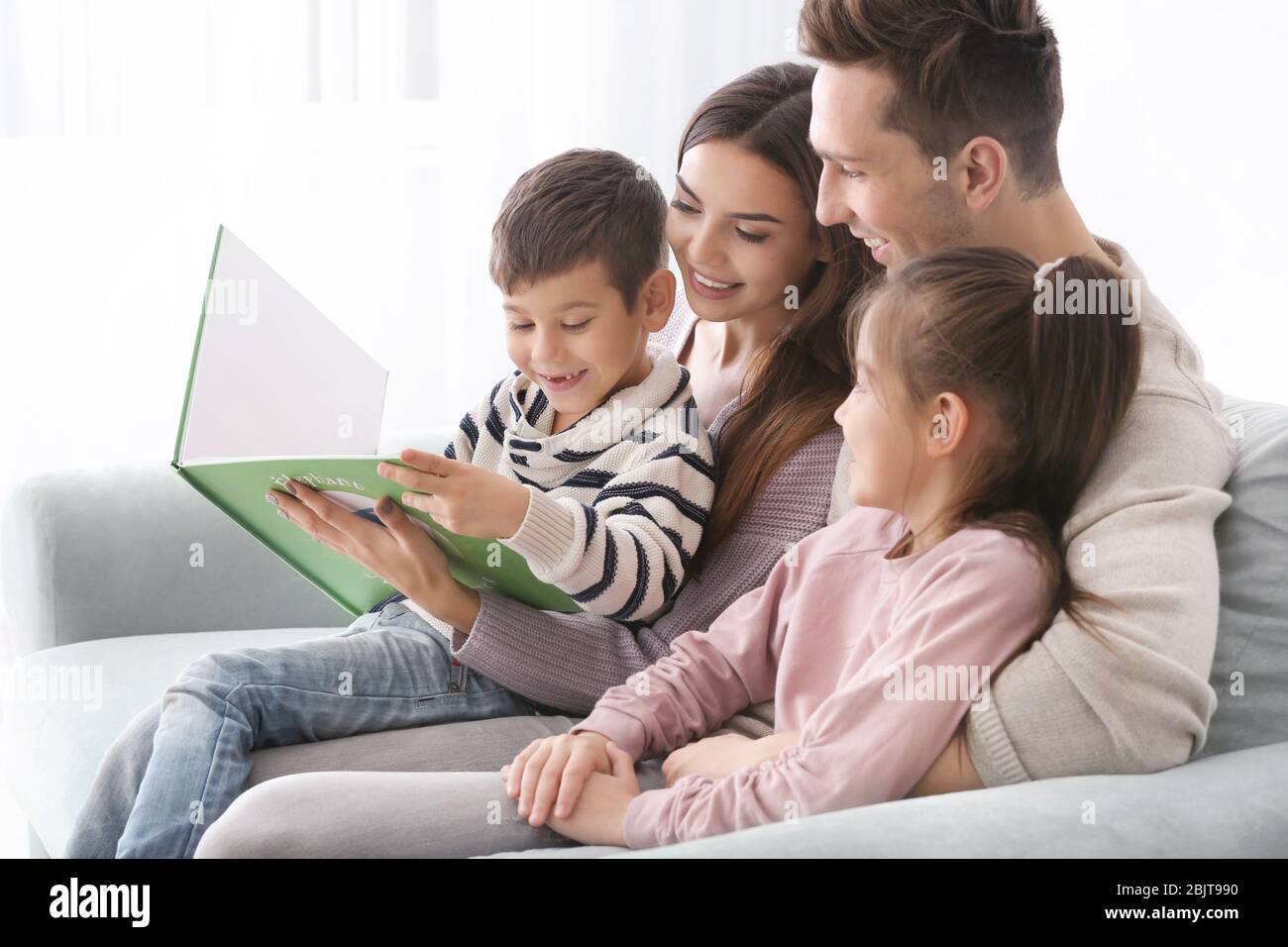 Happy family reading book at home Stock Photo - Alamy