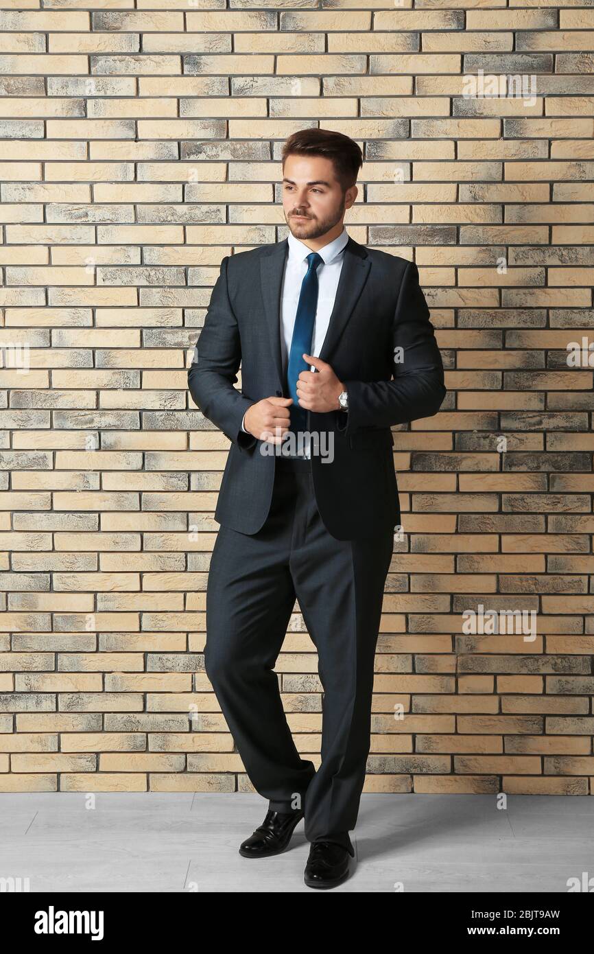 Handsome man in formal suit against brick wall Stock Photo - Alamy