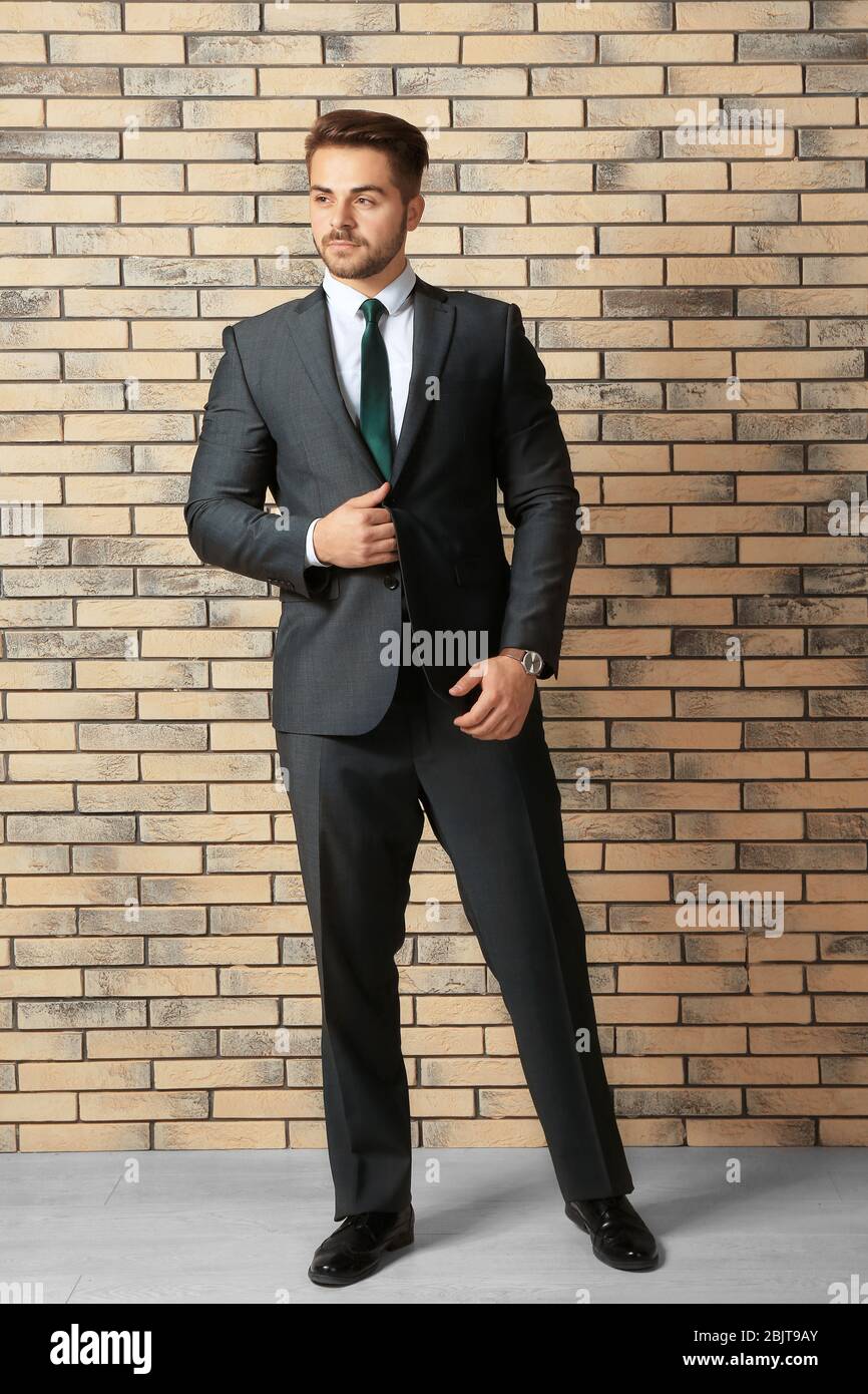 Handsome man in formal suit against brick wall Stock Photo - Alamy