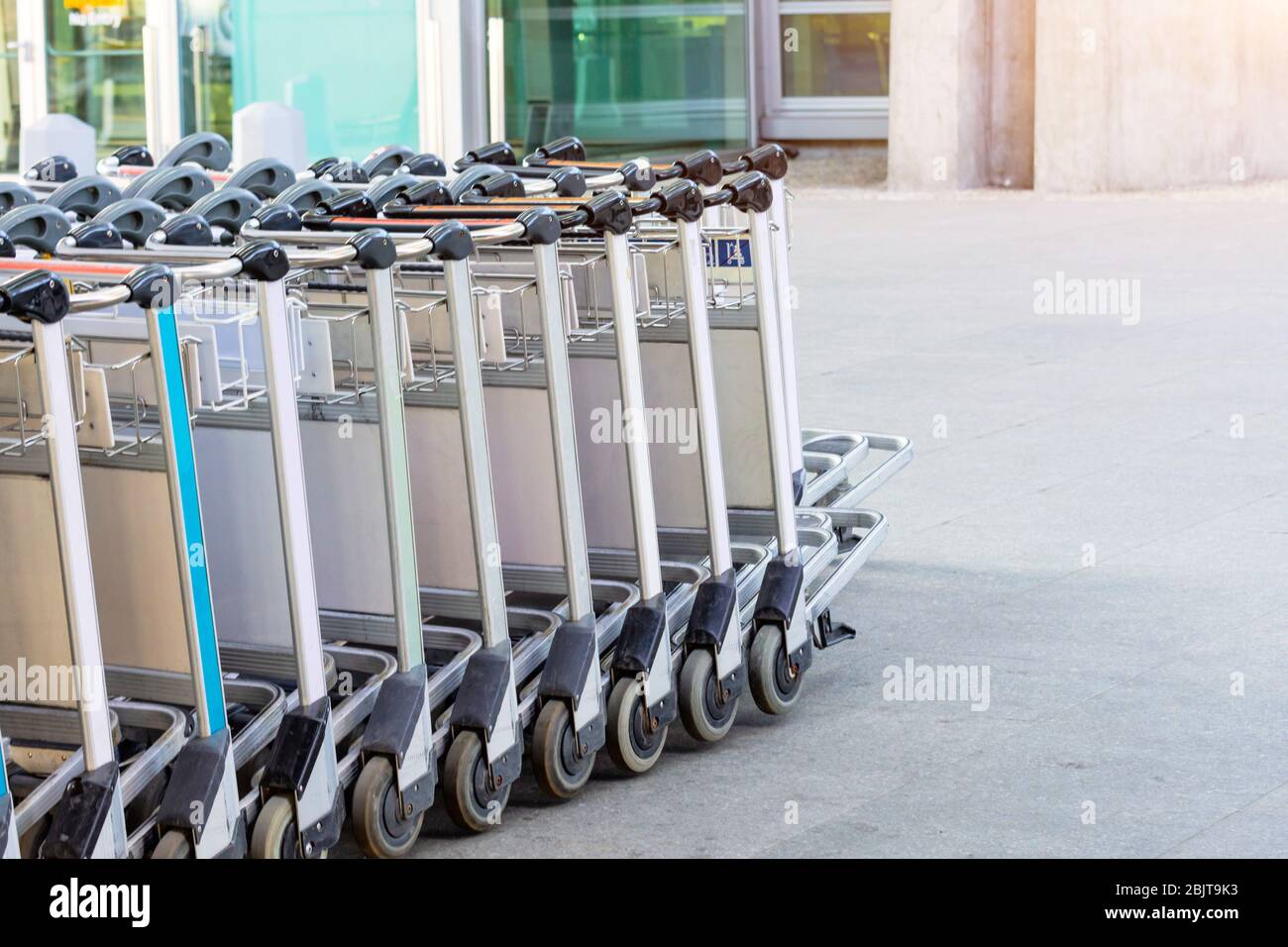 A row of passenger luggage trolleys at the entrance to the airport ...