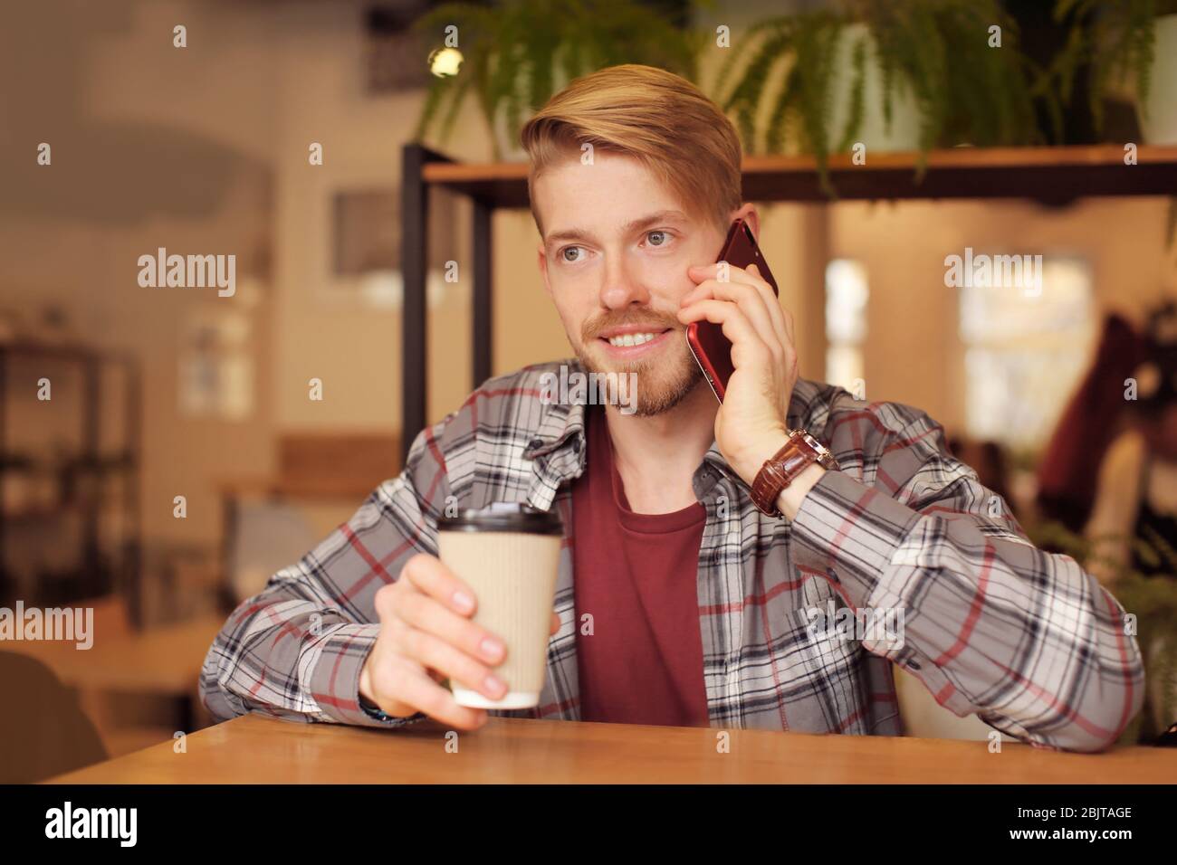 Portrait of trendy hipster drinking coffee while talking on mobile ...