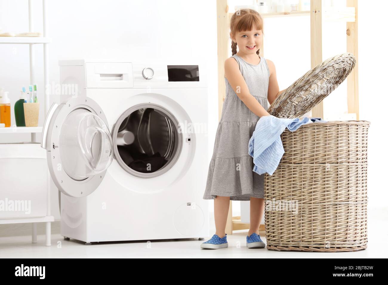 Cute little girl doing laundry indoors Stock Photo - Alamy