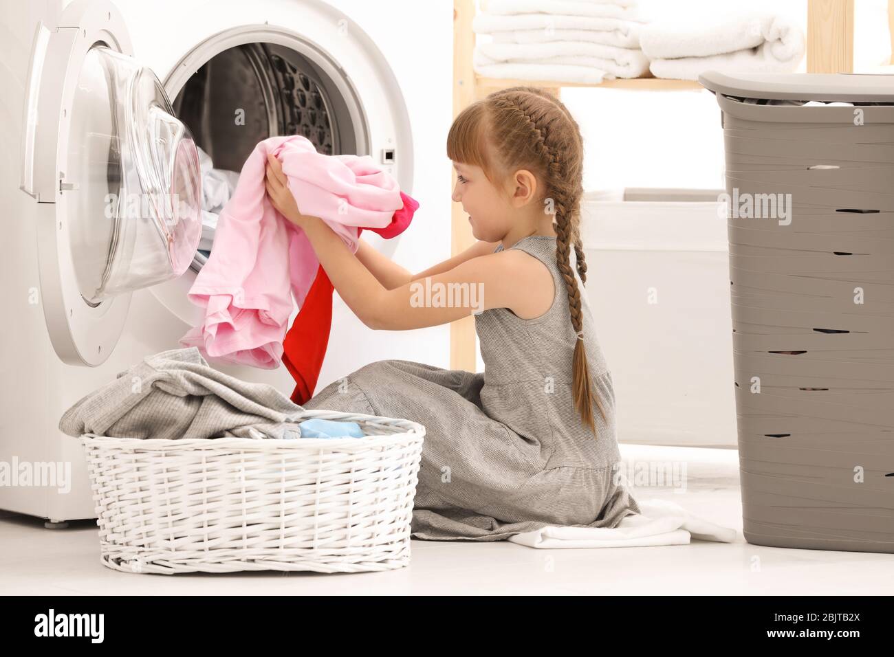 Cute little girl doing laundry indoors Stock Photo - Alamy