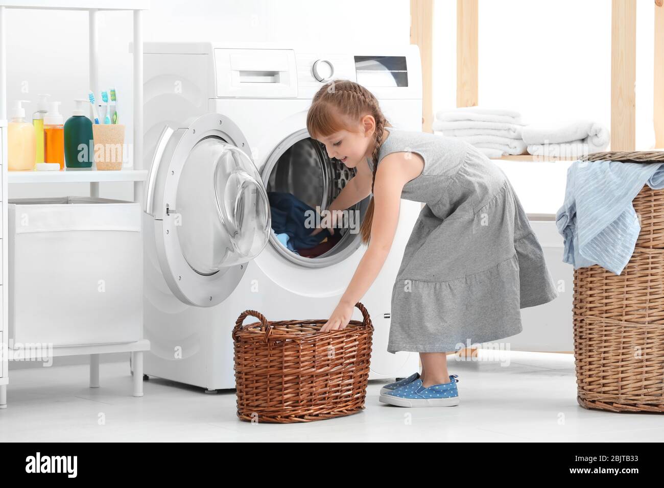 Cute little girl doing laundry indoors Stock Photo - Alamy