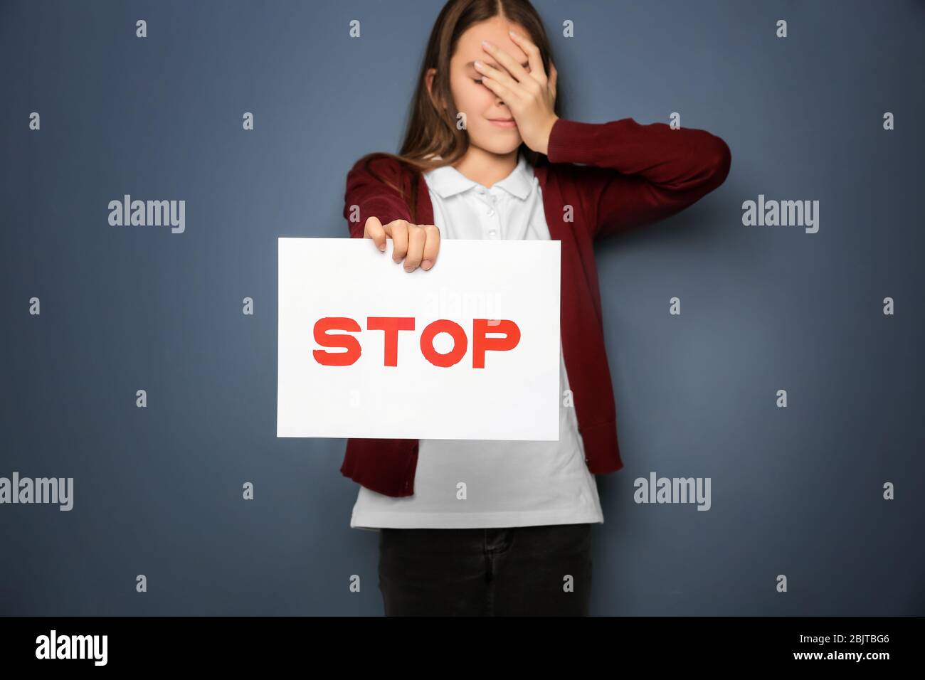 Teenage girl holding sign "Stop" on color background Stock Photo - Alamy