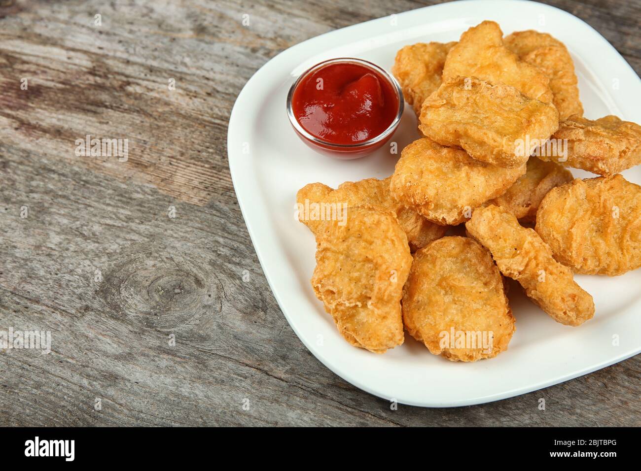 Plate with tasty chicken nuggets and sauce on table Stock Photo - Alamy