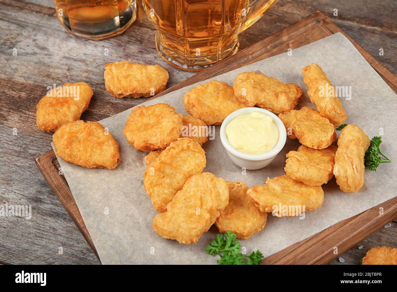 Wooden board with tasty chicken nuggets and sauce on table Stock Photo ...