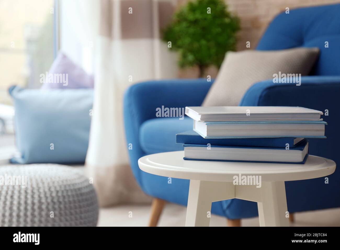 Stack of books on table and armchair in living room Stock Photo - Alamy